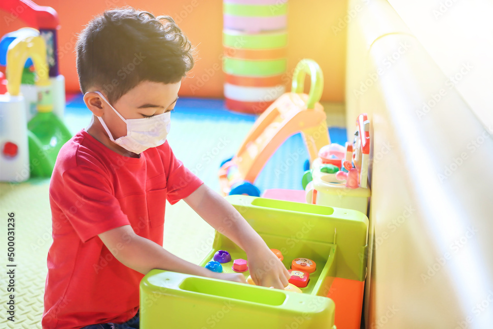 Cute children boy playing indoor playground with face mask protection ...
