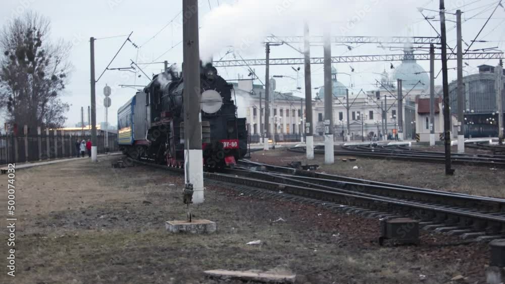 Steam locomotive train approaching station passing through a goods yard ...