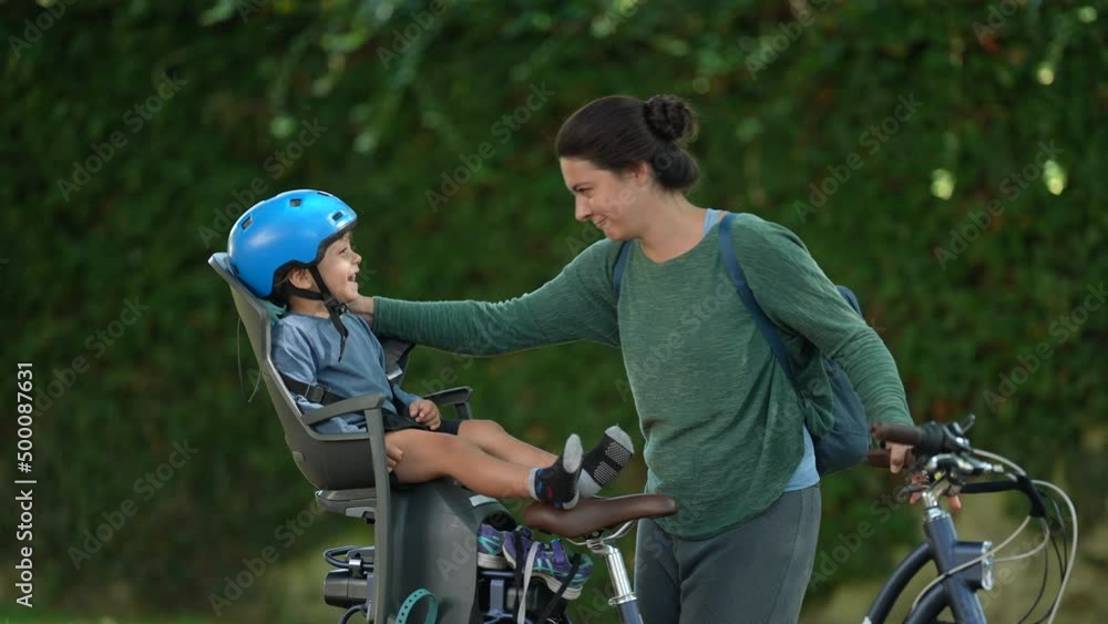 Mother and child together child sitting bicycle seat laughing with mom ...