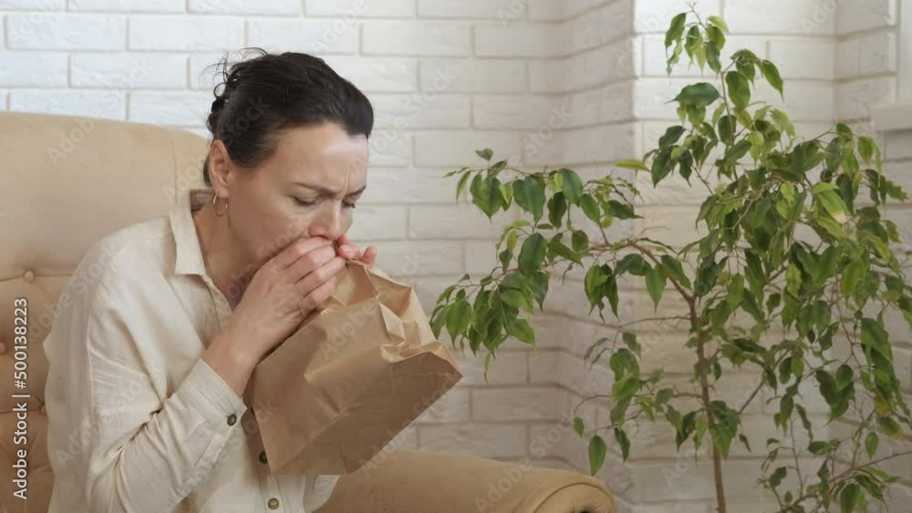 Breathing using paper bag. A stressed woman breath into her paper bag ...