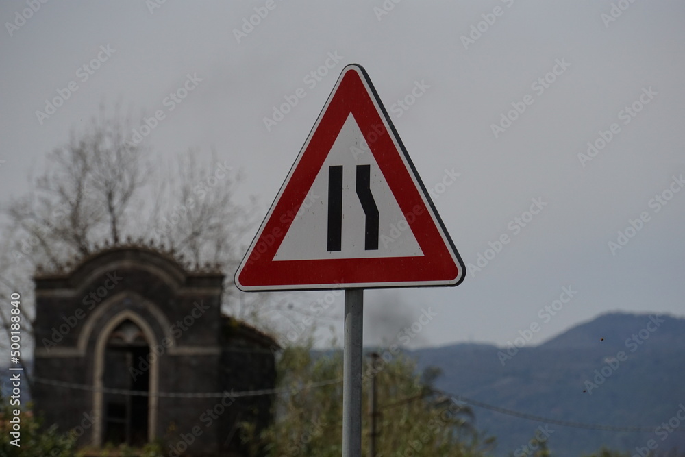 Segnale stradale strettoia asimmetrica a destra con una casetta rudere ...