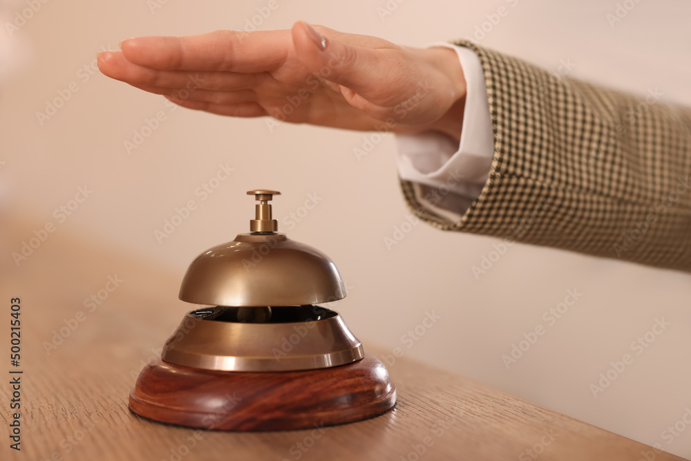 Woman ringing hotel service bell at wooden reception desk, closeup ...