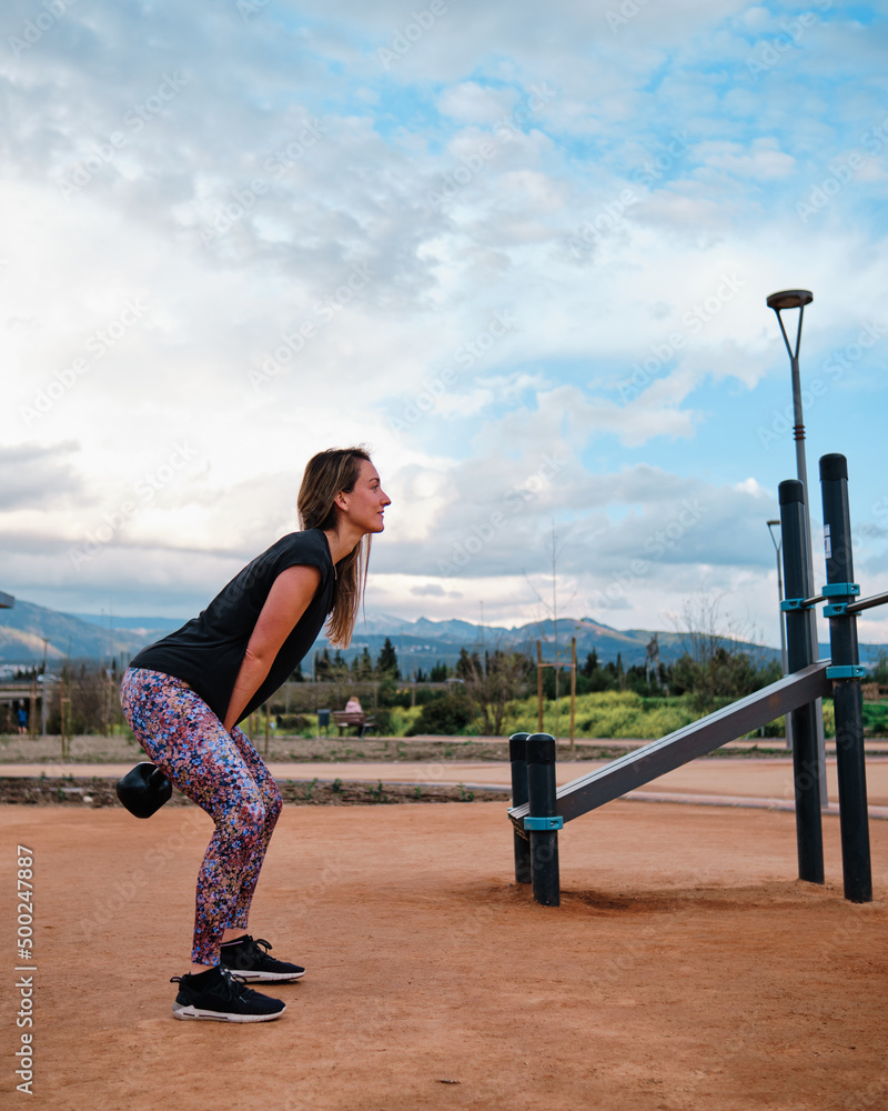 Young blonde woman performing calisthenics exercises in an urban park ...