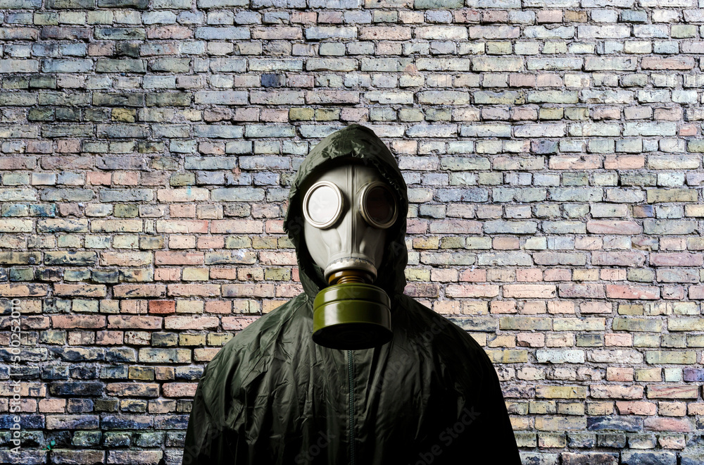 Gas mask. Man wearing a gas mask on his face and the wall behind him ...