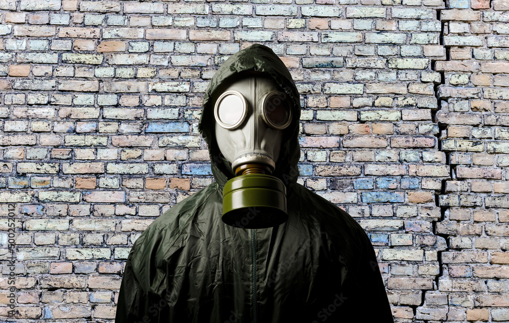 Gas mask. Man wearing a gas mask on his face and the wall behind him ...