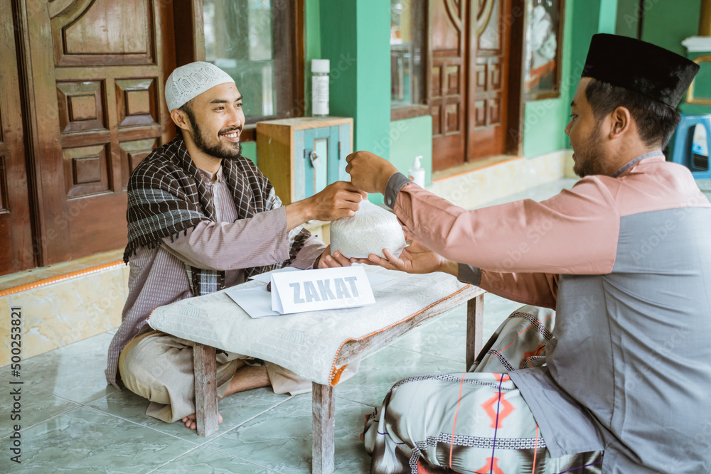 portrait of happy muslim man giving a rice as a food donation for zakat ...
