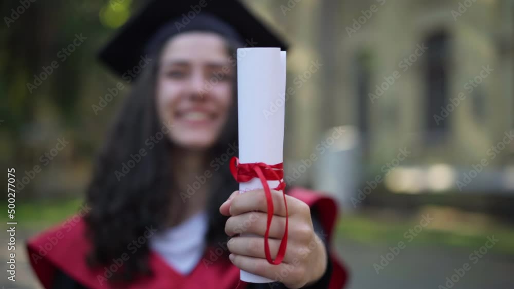 Close-up diploma with red ribbon in female hand with blurred smiling ...
