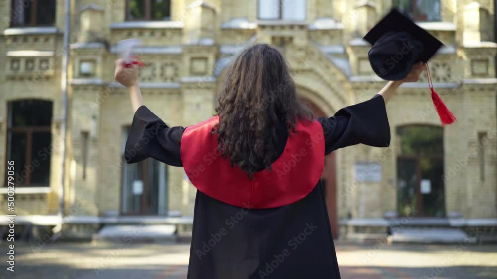 Excited female student in graduation toga stretching hands with diploma ...
