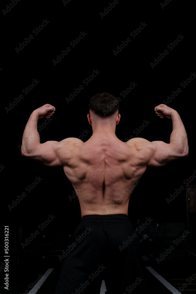 Foto de Bodybuilder handsome strong athletic rough man pumping up back ...