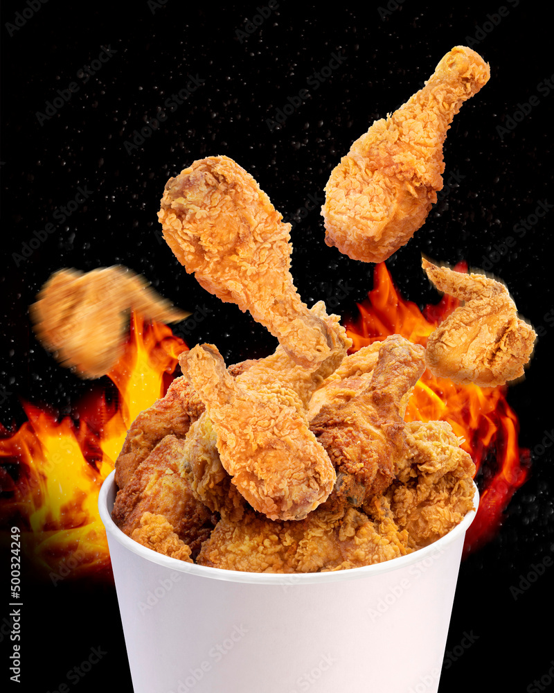 Fried chicken flying out of paper bucket over hot flame background, Hot ...