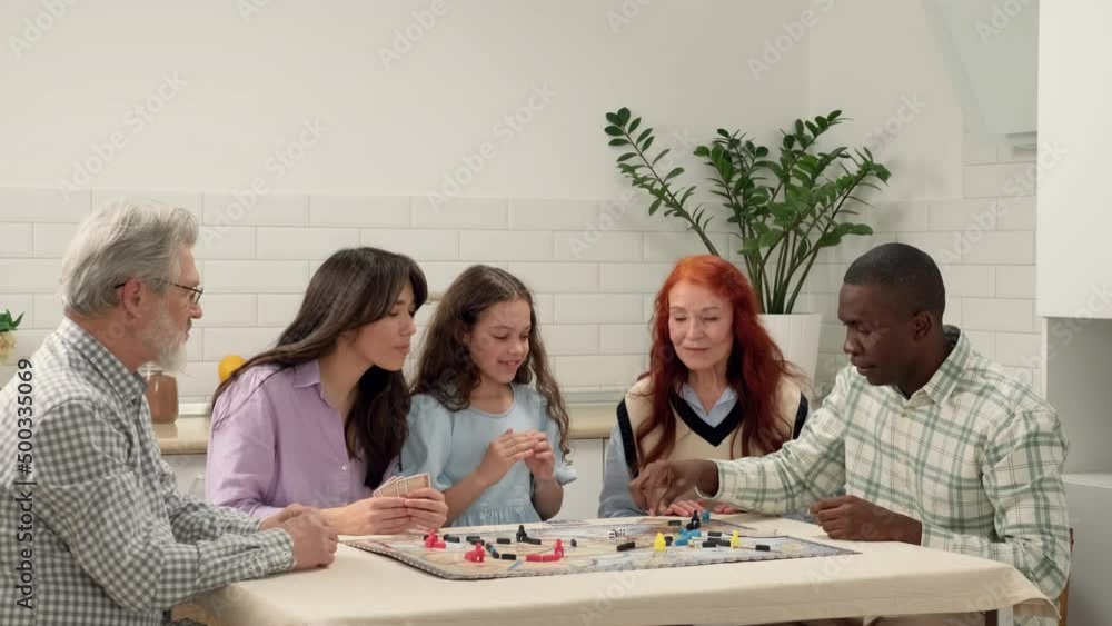 Multi Ethnic family of different age generations play board game at ...