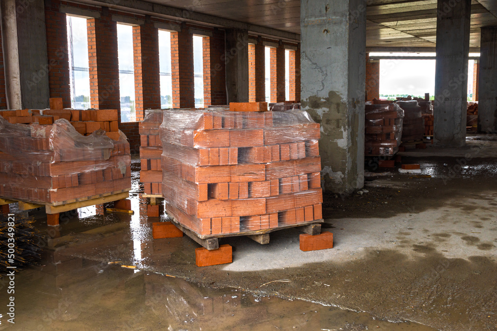 Pallets of bricks stand inside a monolithic frame building under ...