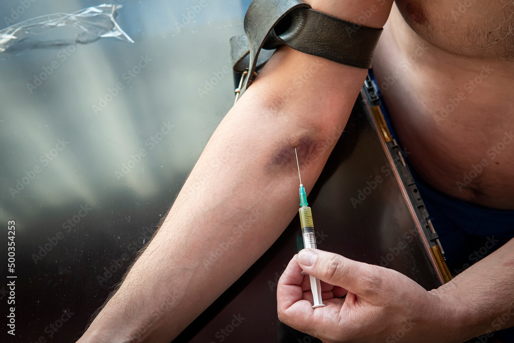 Foto de Addict injecting heroin dose to his hand with syringe. Man ...