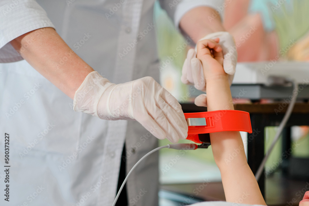 Doctor applying ECG electrodes on child hand for pediatric ...