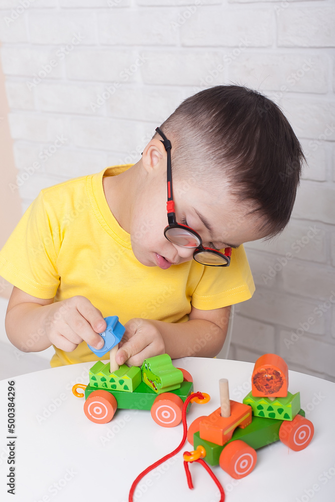Motor therapy. Boy with down syndrome playing with toy and doing ...