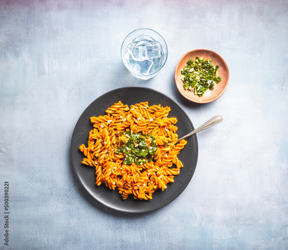 Curly pasta macaroni with tomato and gremolata sauce in a round dark ...