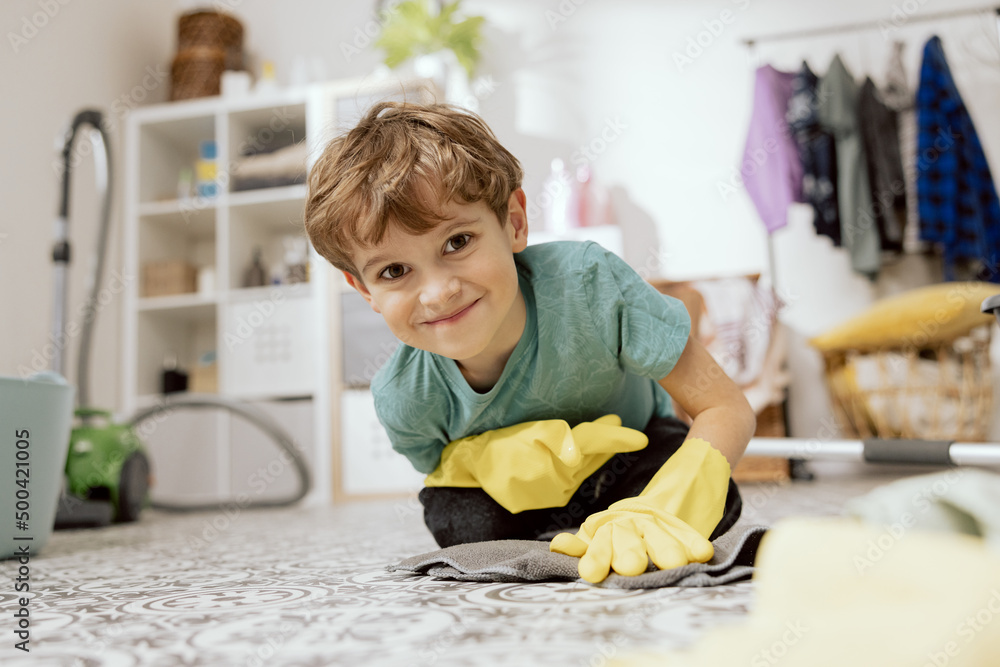 Boy learning how to use disinfectant spray bottle cleaning and mopping ...