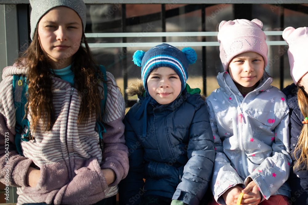 Three Ukrainian children sitting on station and waiting for transport ...