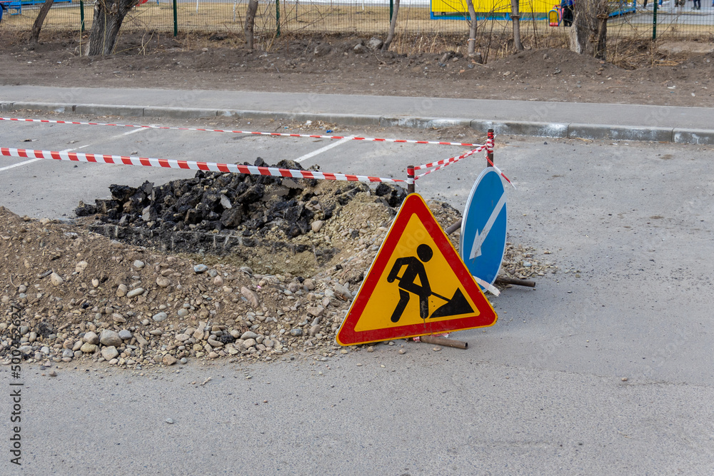 A trench dug in the middle of the road is fenced with road signs and ...