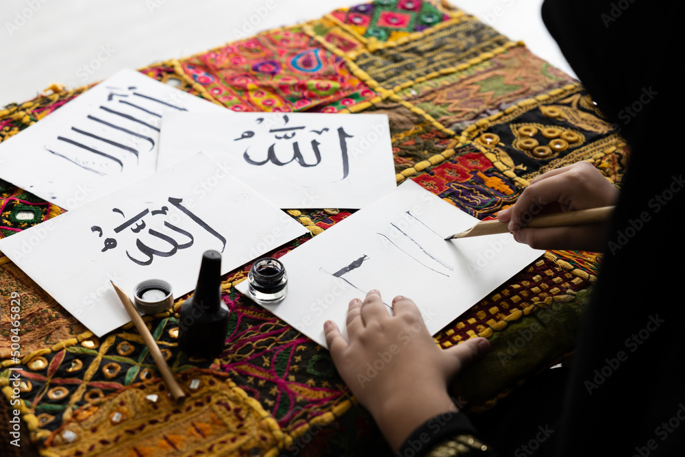 close up muslim girl hands writing Arabic text with bamboo pens and ...