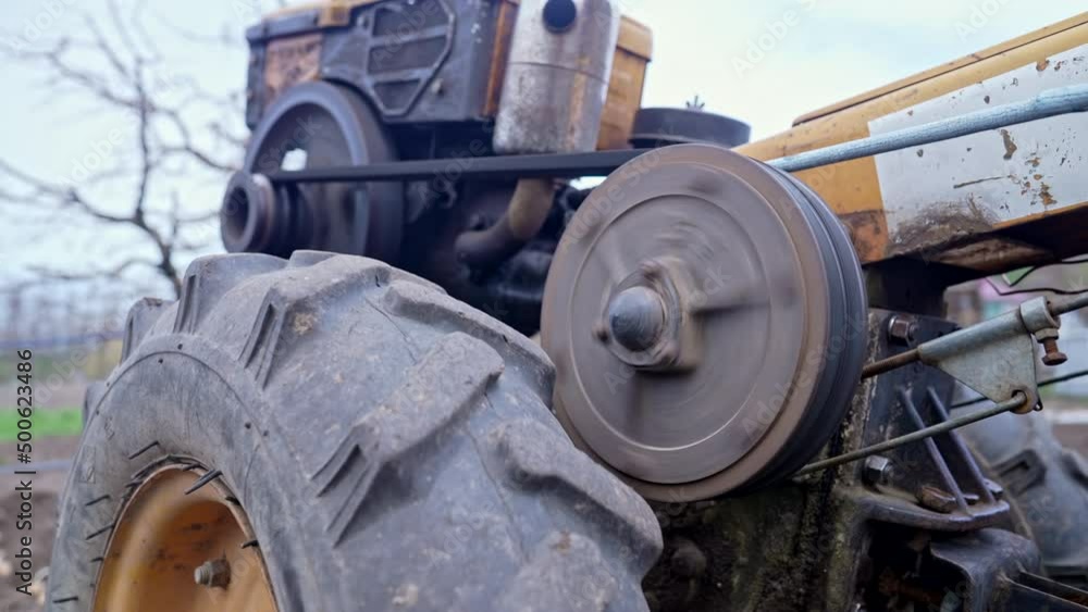 Working process of rotating pulley with belt. Man works in garden with ...