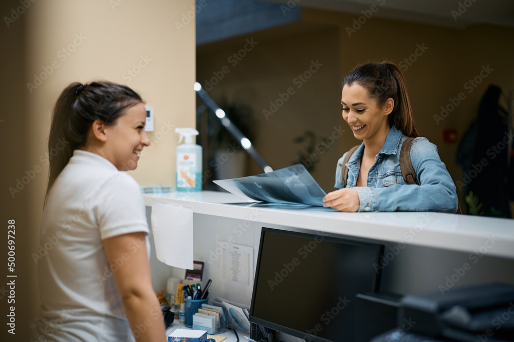 Happy woman looking at her X-ray scan at reception desk of physical ...