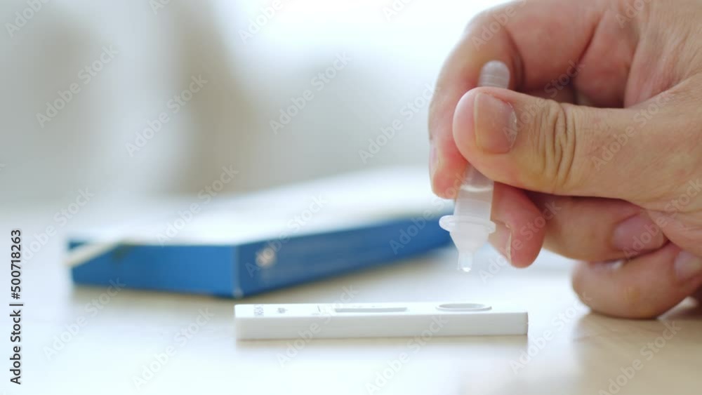 CLoseup hand using rapid antigen test kit (ATK) for self test at home ...