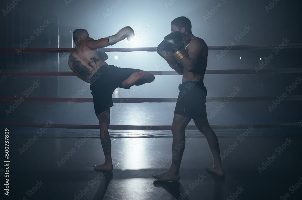 Two shirtless muscular man fighting Kick boxing combat in boxing ring ...