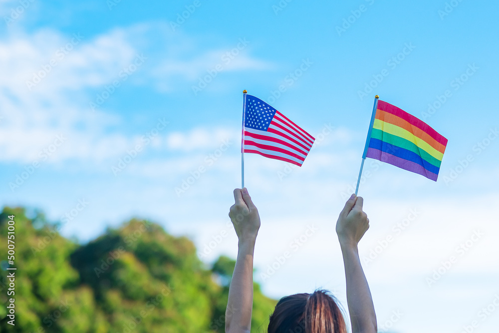 hands showing LGBTQ Rainbow and America flag on nature background ...