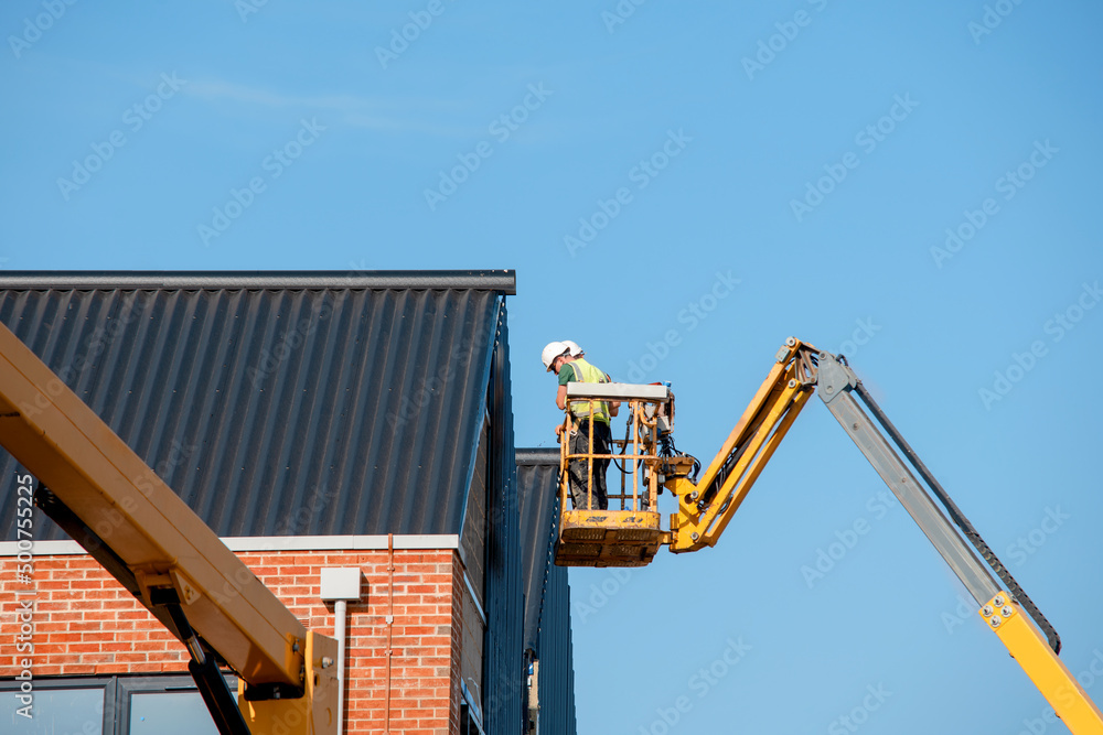 Foto de Builders working off Telescopic Boom Lift while fitting ...