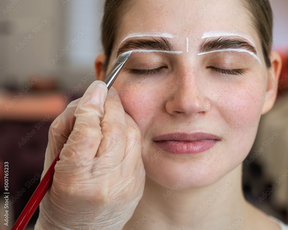 The master draws the shape of the eyebrows with white paint before ...