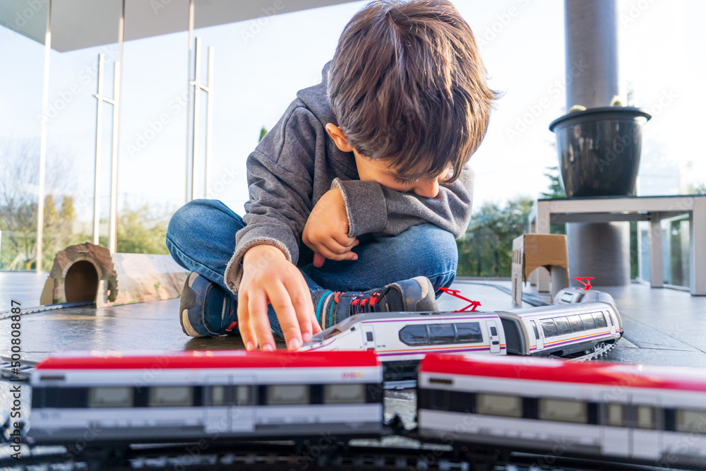 Young kid playing with toy trains on the floor. Toy train similar to ...