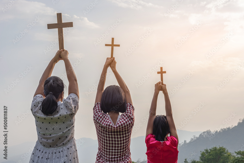 Children praying to the GOD while holding a crucifix symbol with bright ...