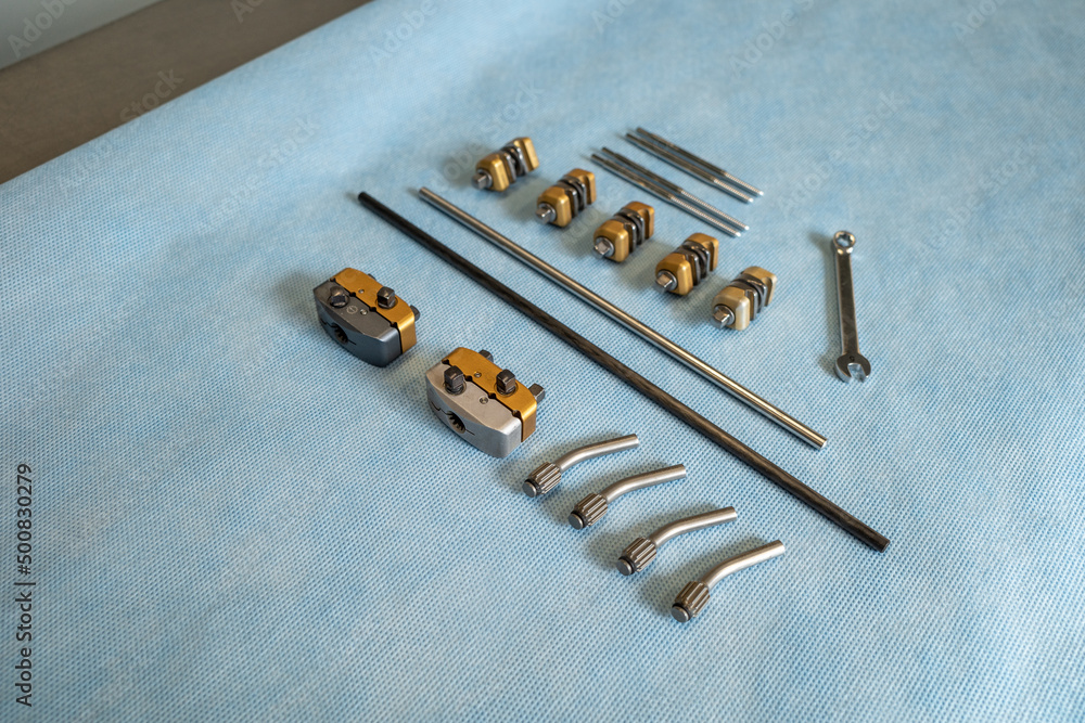 single parts of a surgical hand fixator lie on a blue surgical cloth ...