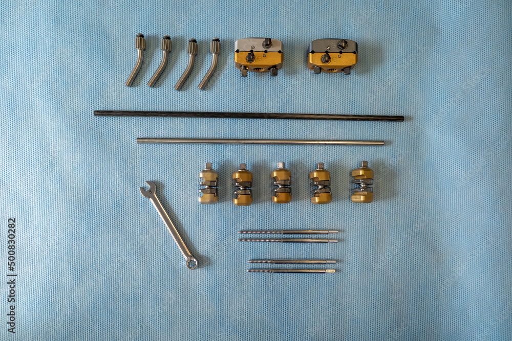 single parts of a surgical hand fixator lie on a blue surgical cloth ...