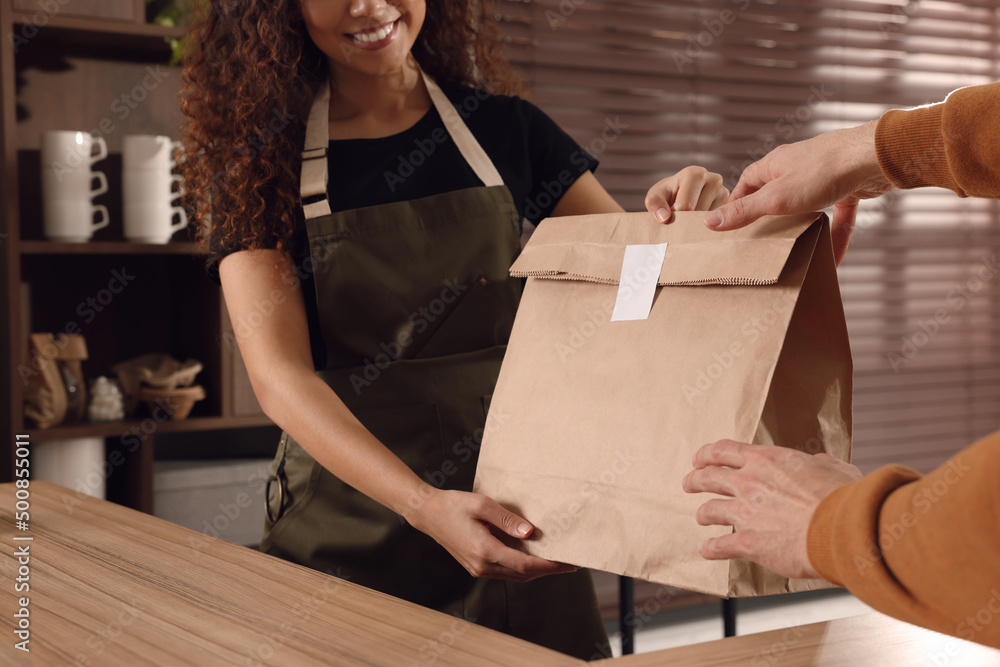 Worker giving paper bag to customer in cafe, closeup Stock Photo ...