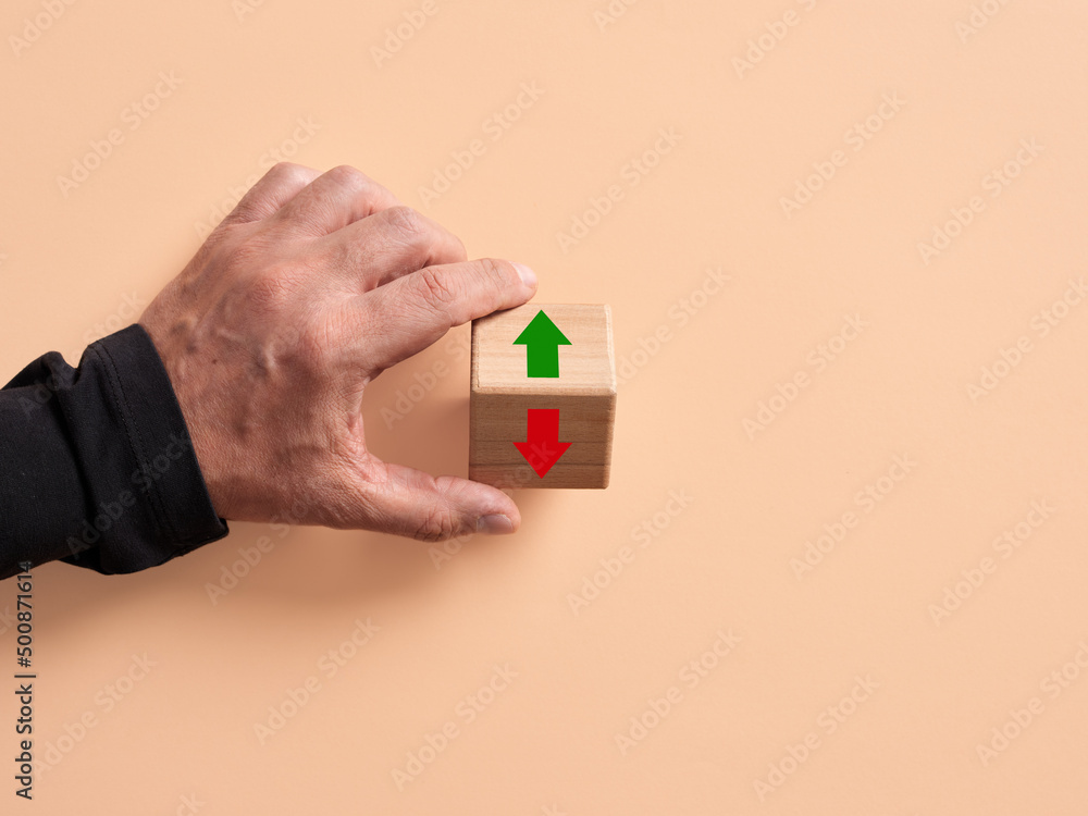 Hand turns the wooden cube with down and up arrow symbols. Growth ...