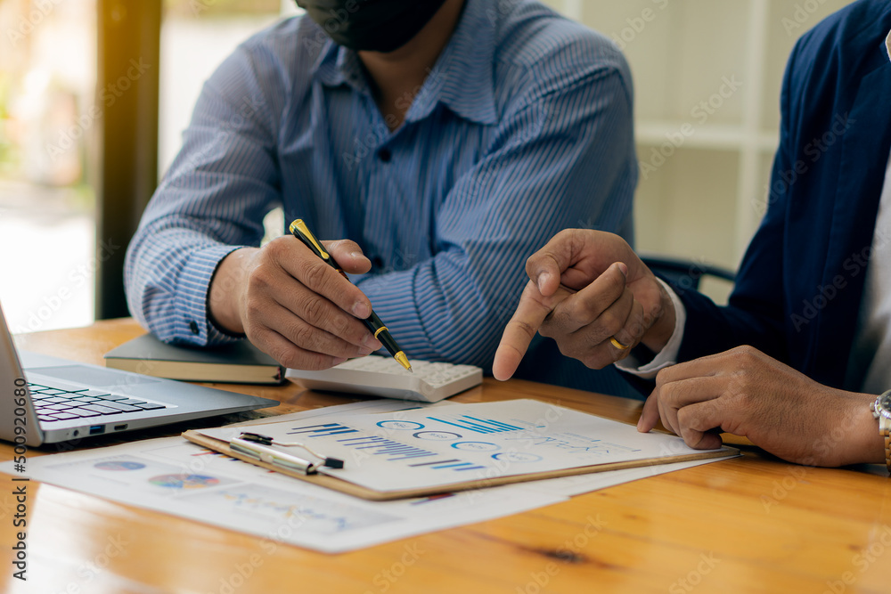 2 businessmen with pens pointing to financial charts for analysis ...