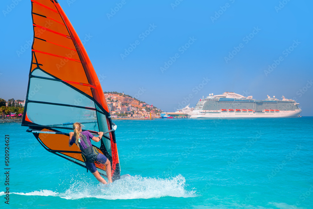 Windsurfer surfing the wind on sea waves - The cruise ship is located ...