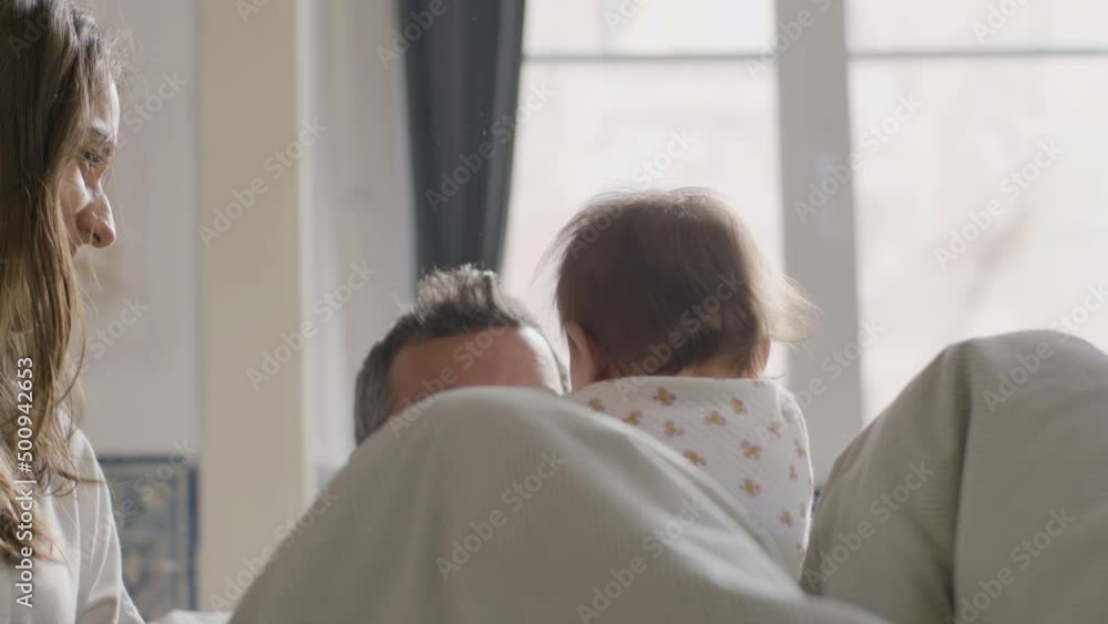 Happy married couple enjoying lazy weekend morning cuddling in bed with ...