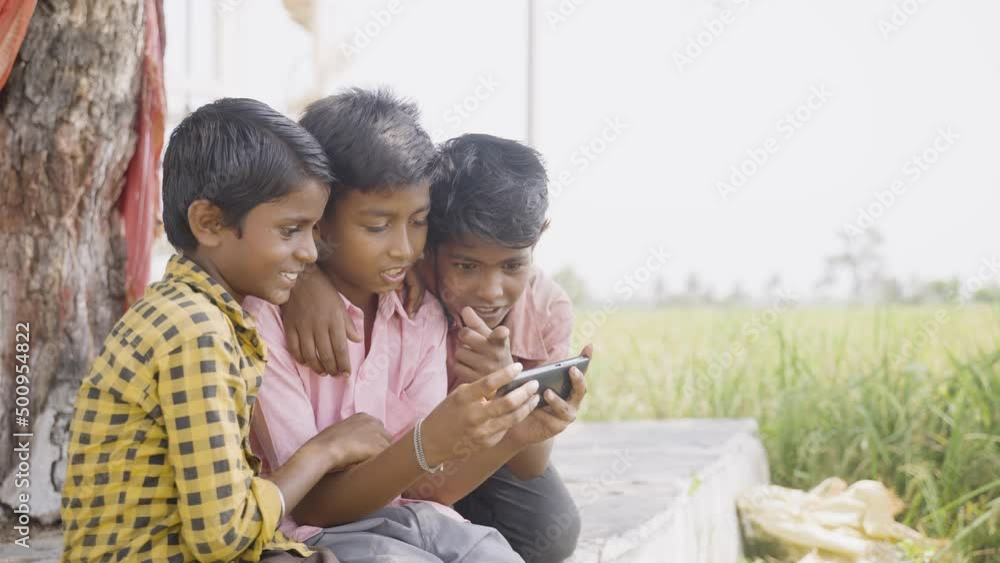 Indian village teenage kids playing video game on mobile phone near ...