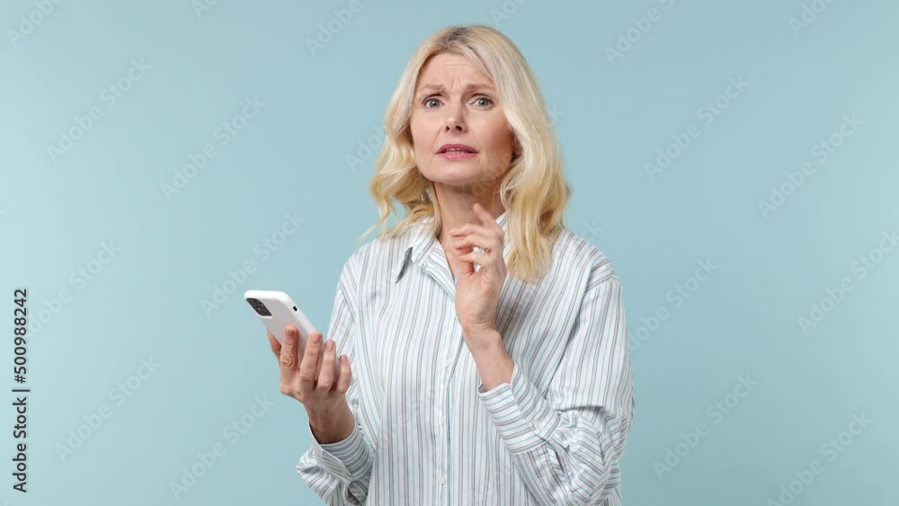 Perplexed elderly gray-haired blonde woman lady 40s years old wears white shirt hold use chat ...