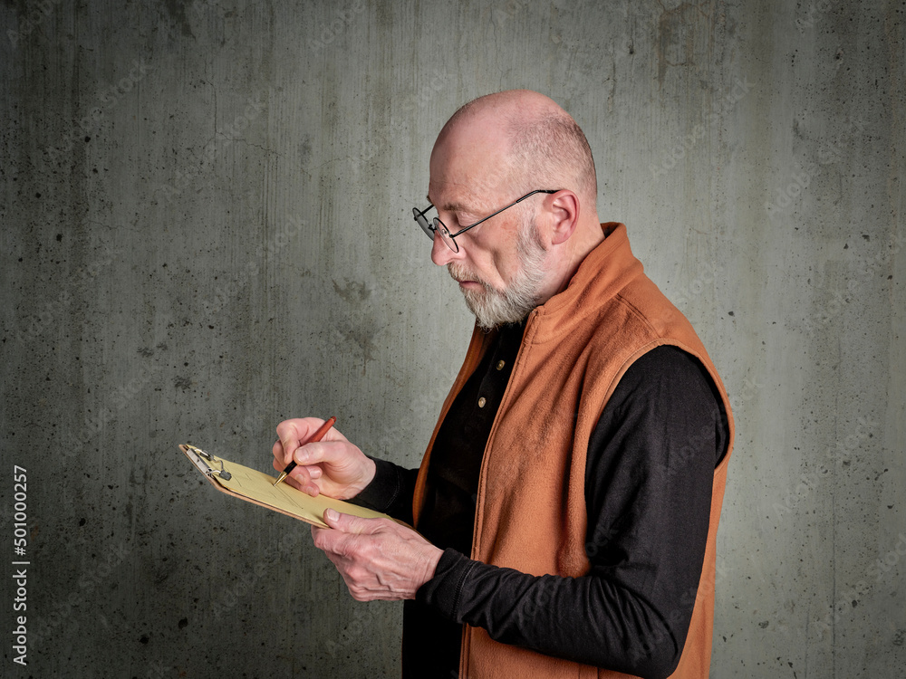 Head and shoulders portrait of a senior, bald and bearded man writing ...