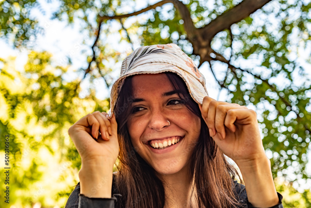 Young playful woman pulling down her hat Stock Photo | Adobe Stock