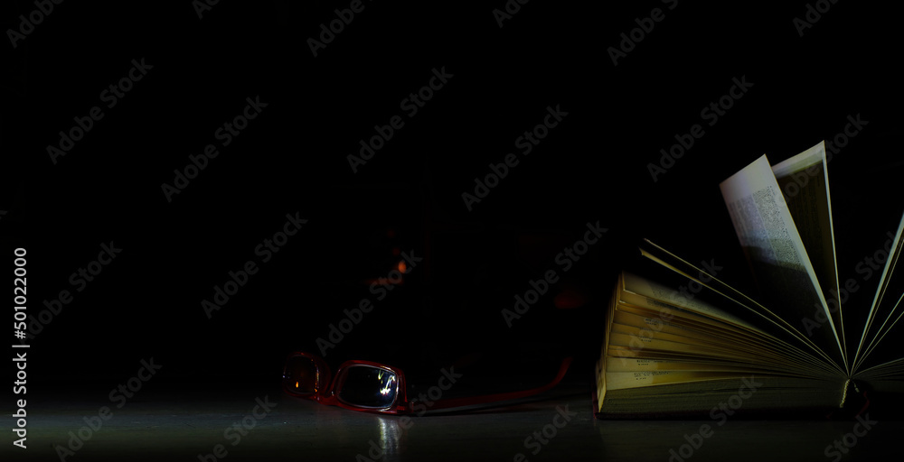 Open book, hardback book and specs on dark background. Back to school ...