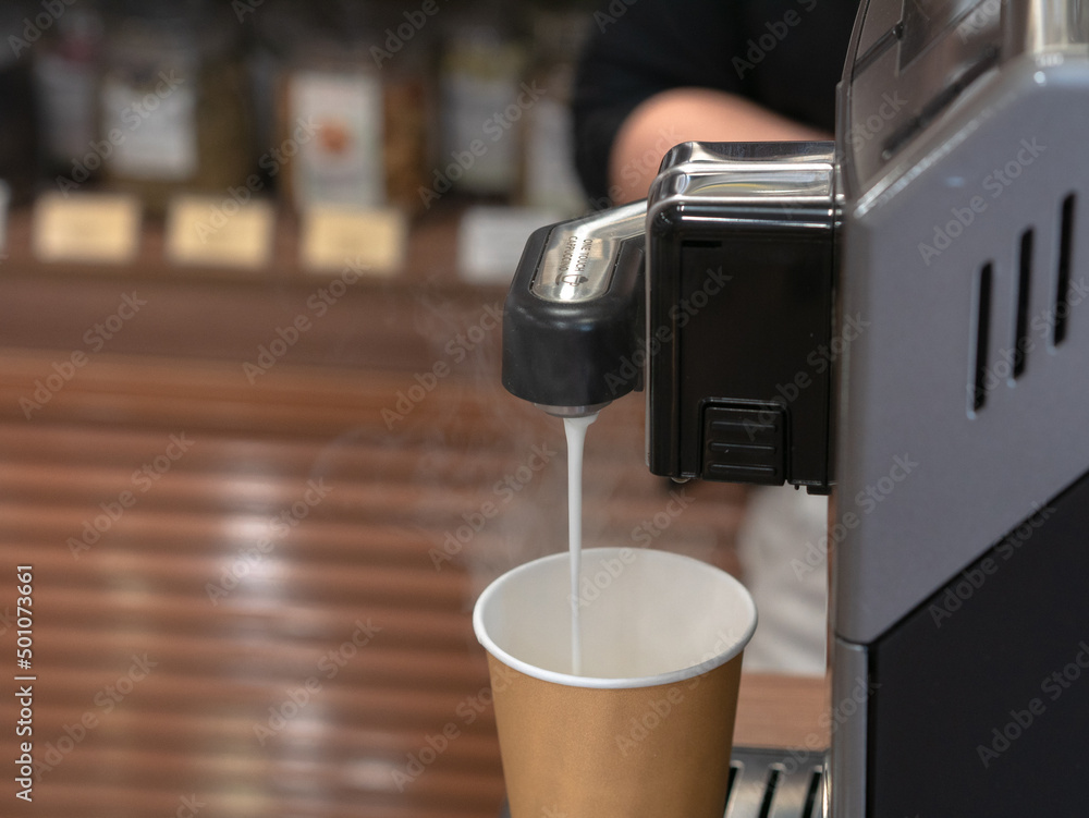 Disposable paper cup hot jet of milk with steam pouring from a coffee ...