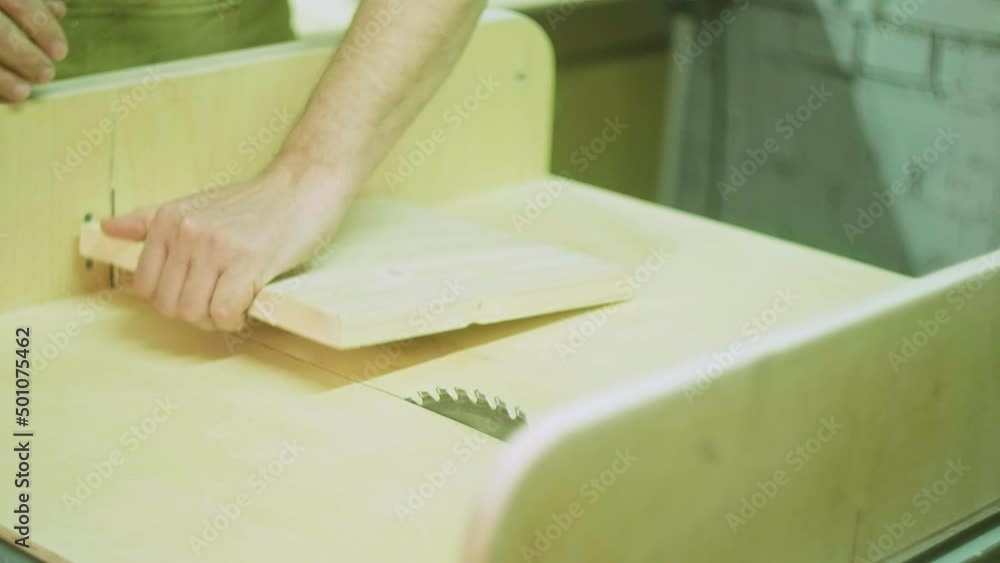 A mature man makes a right angle with a square and saws boards on a ...