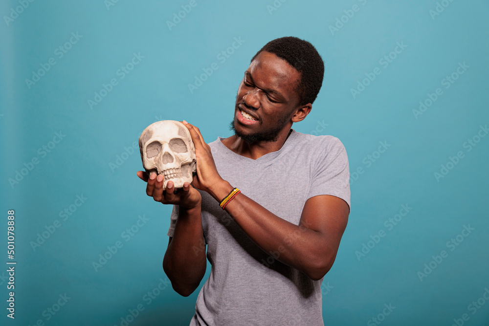 Portrait of young guy holding skull from human skeleton to study ...