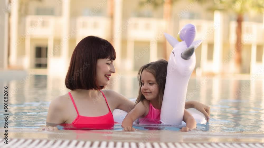 Mom and daughter swim together in the pool with an inflatable ring in ...