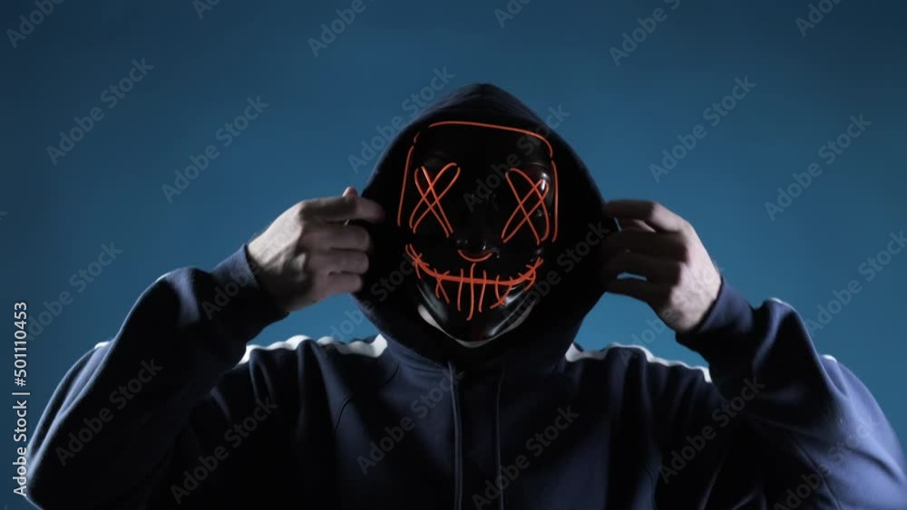 Man in creepy mask wearing hood. Mystery man. Halloween concept at blue ...